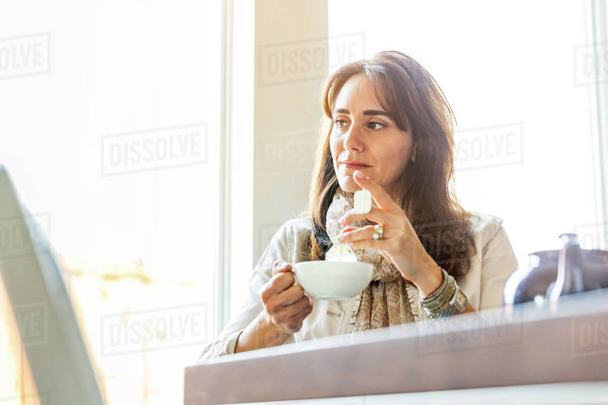 Caucasian woman drinking tea at table - Stock Photo - Dissolve