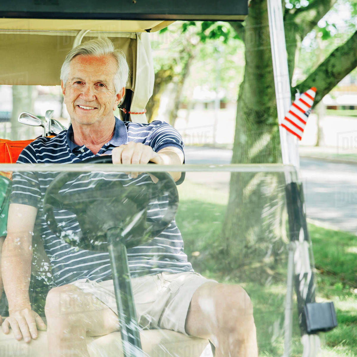 Older Caucasian man driving golf cart - Stock Photo - Dissolve