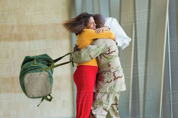 African American soldier hugging wife in airport - Stock Photo - Dissolve