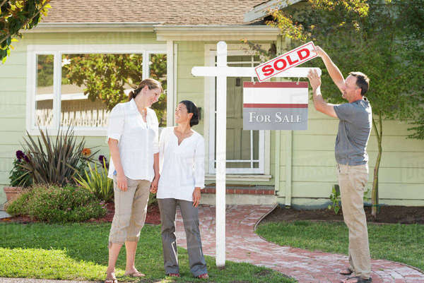 Real estate agent hanging sign outside house - Stock Photo - Dissolve