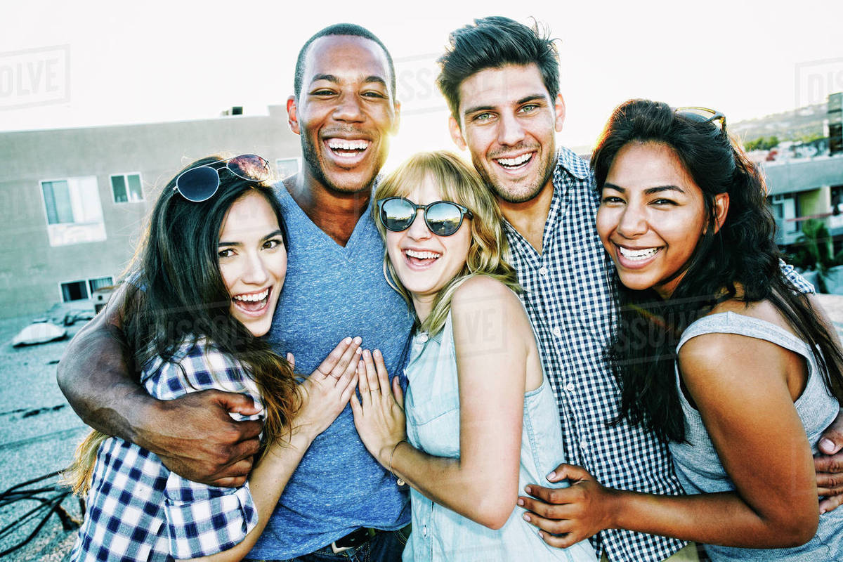 Friends hugging on urban rooftop - Stock Photo - Dissolve