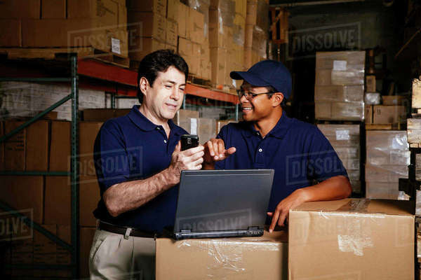 Warehouse workers using laptop and cell phone - Royalty-free Stock ...
