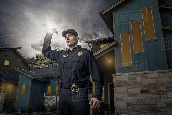 Caucasian police officer shining flashlight near house - Royalty-free ...