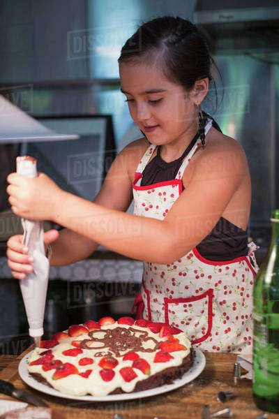 Caucasian girl decorating cake in kitchen - Stock Photo - Dissolve