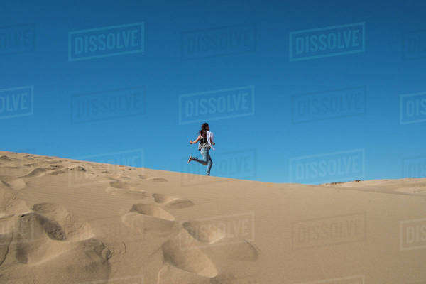 Caucasian woman running on sand dune - Royalty-free Stock Photo | Dissolve