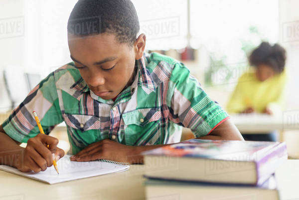 Black student writing in classroom - Royalty-free Stock Photo | Dissolve
