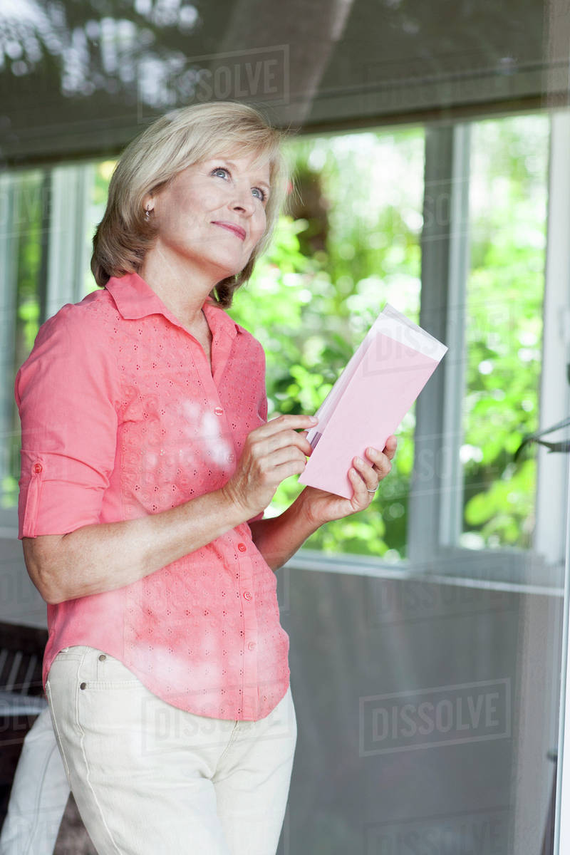 Smiling Caucasian woman reading card - Royalty-free Stock Photo | Dissolve