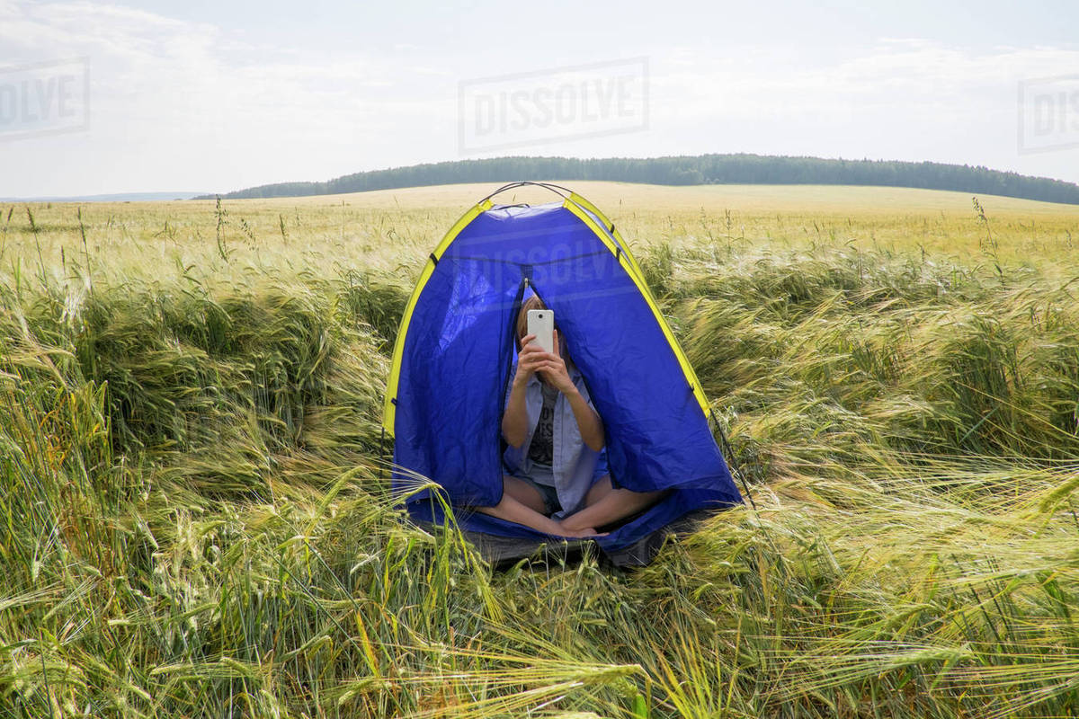 Caucasian women sitting in tent taking cell phone selfie - Royalty-free ...