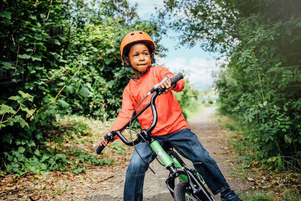 Black boy riding bicycle with helmet - Royalty-free Stock Photo | Dissolve