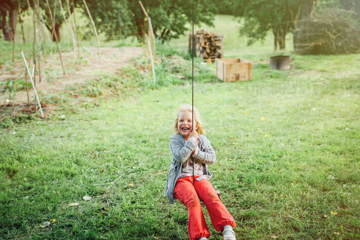 Smiling Caucasian girl on rope swing - Royalty-free Stock Photo | Dissolve