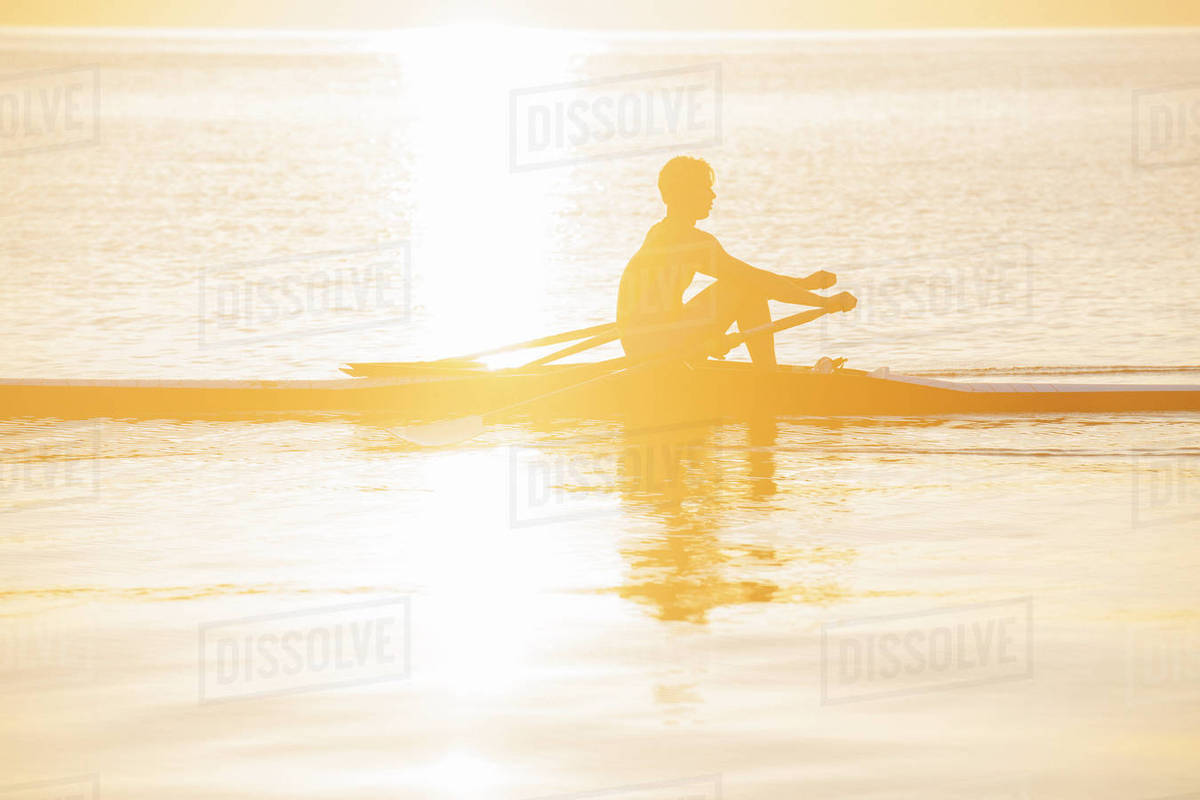 Silhouette of Caucasian man rowing on lake - Stock Photo - Dissolve