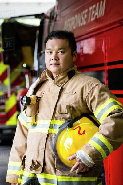 Serious Chinese fireman standing near fire truck - Stock Photo - Dissolve
