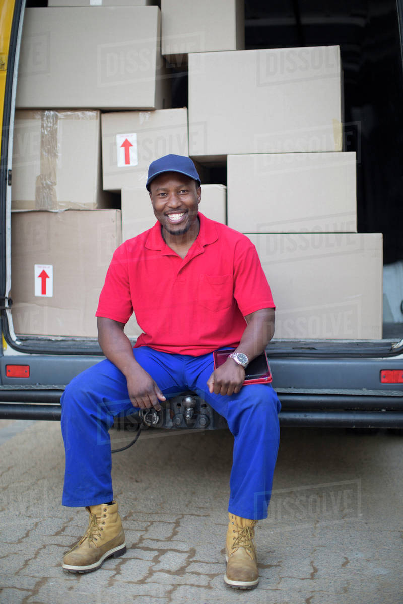 Black delivery man sitting with packages in van - Royalty-free Stock ...