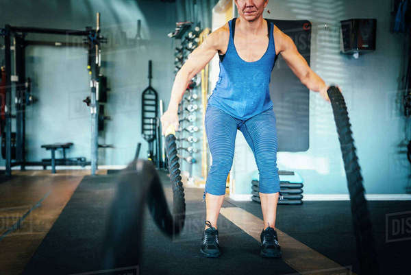 Woman using ropes in gymnasium - Royalty-free Stock Photo | Dissolve