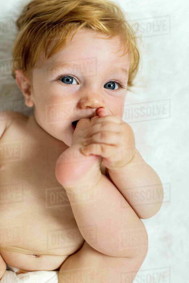 Baby boy biting foot - Stock Photo - Dissolve