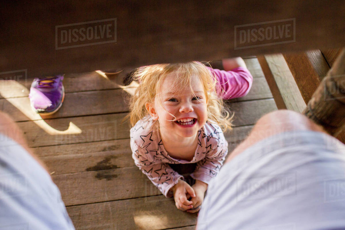 Portrait of smiling Caucasian girl laying underneath table - Royalty ...