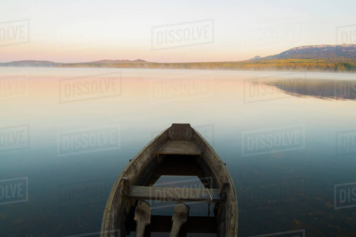 Empty rowboat on lake at sunset - Stock Photo - Dissolve
