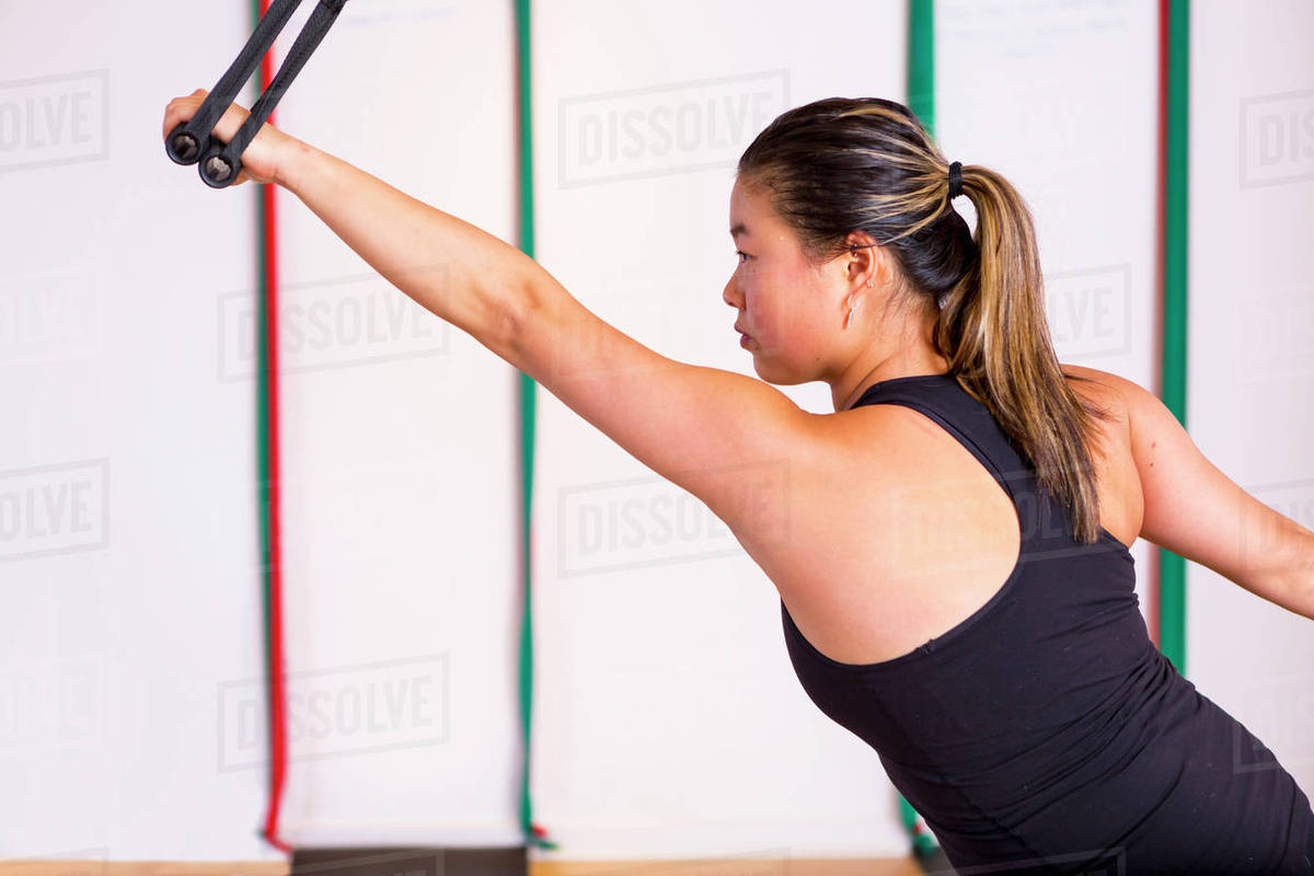 Asian woman holding handle in gymnasium - Stock Photo - Dissolve
