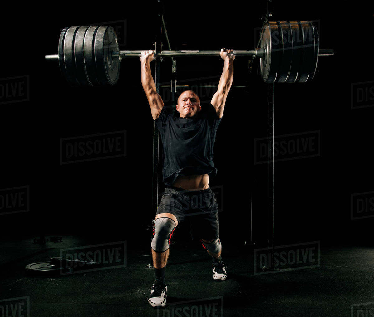 Man lifting heavy barbell in gymnasium - Stock Photo - Dissolve