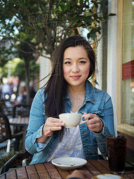 Smiling Chinese woman drinking coffee at outdoor cafe - Royalty-free ...