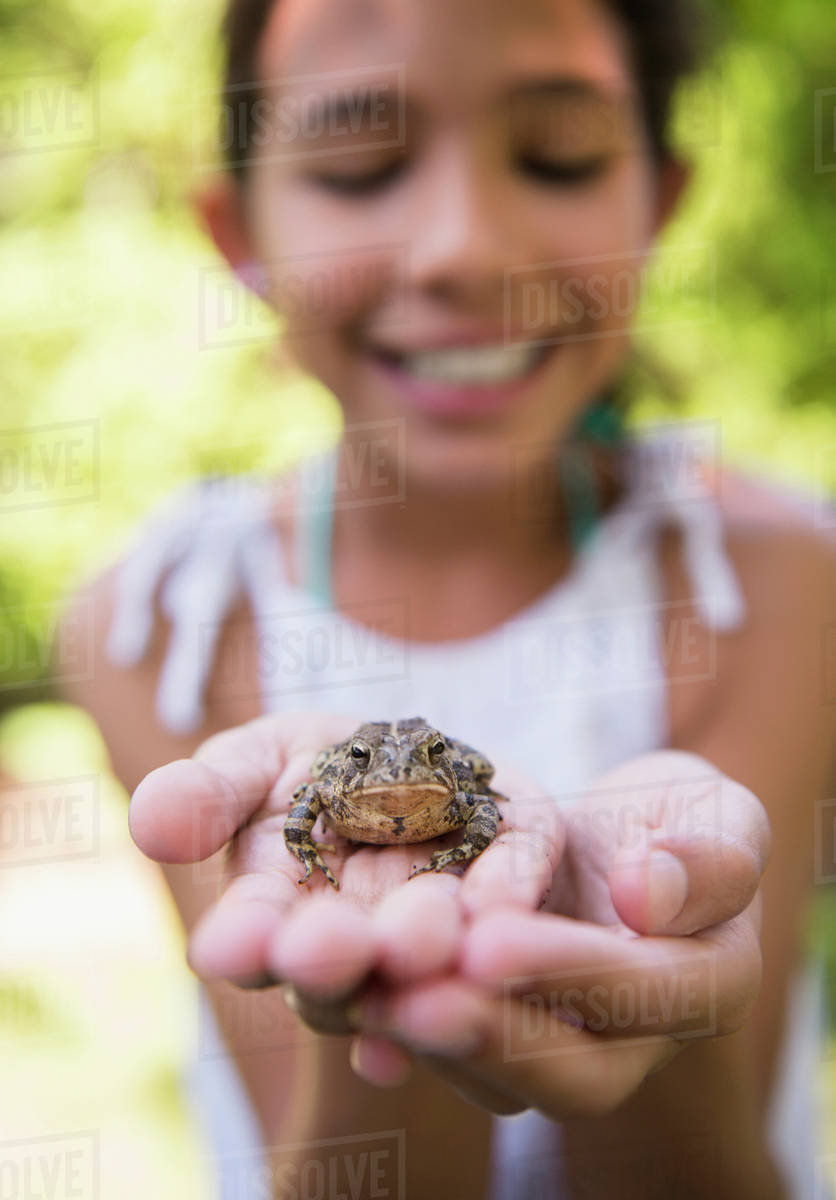 Mixed race girl holding frog outdoors - Royalty-free Stock Photo | Dissolve