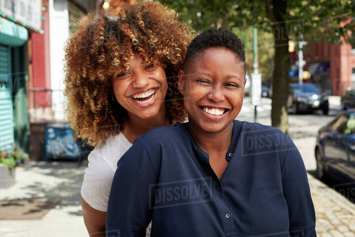 Women smiling on city sidewalk - Stock Photo - Dissolve