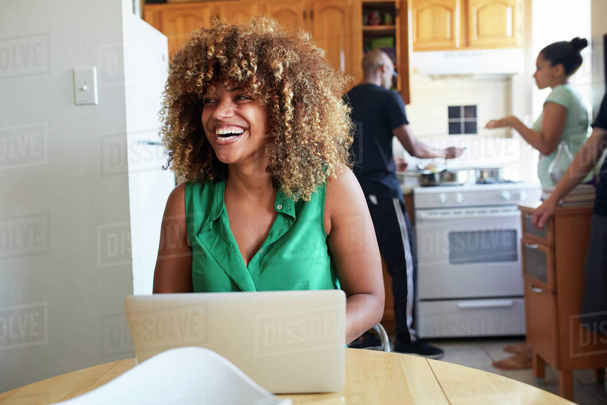 Laughing woman using laptop at table - Royalty-free Stock Photo | Dissolve