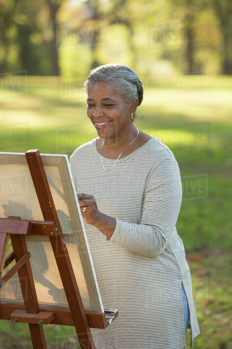 Woman painting on canvas in park - Royalty-free Stock Photo | Dissolve