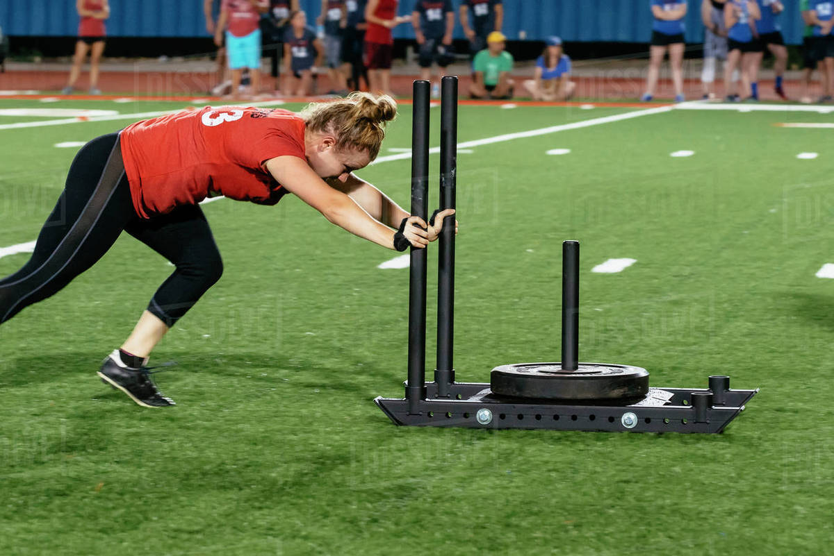 Woman pushing weight on sports field - Royalty-free Stock Photo | Dissolve