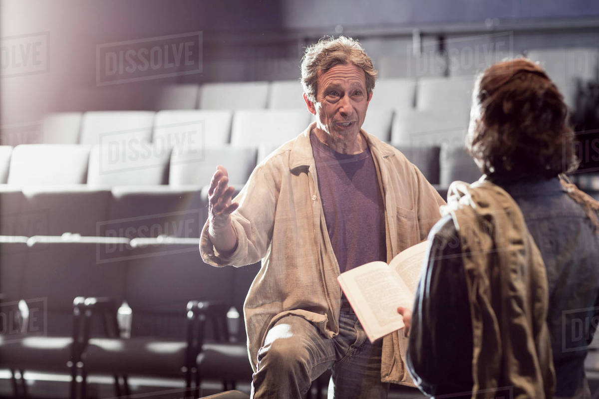 Actors rehearsing with script in theater - Stock Photo - Dissolve