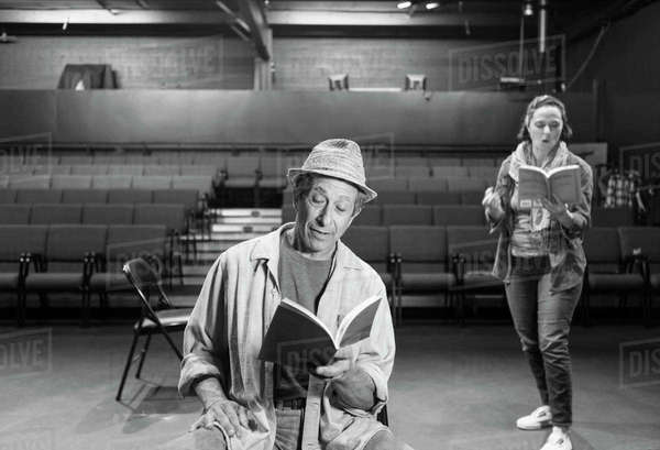 Actors rehearsing with scripts in theater - Stock Photo - Dissolve