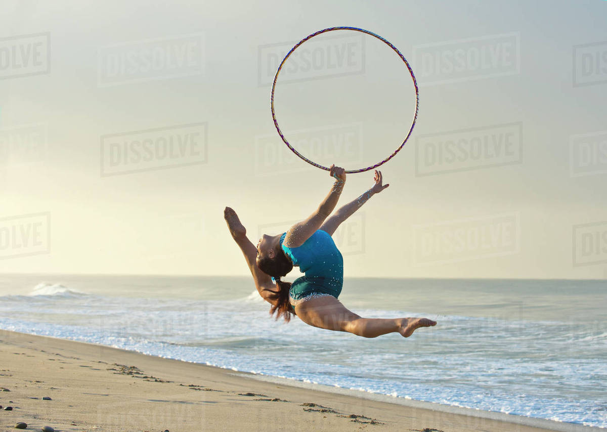 Gymnast jumping with hoop on beach - Royalty-free Stock Photo | Dissolve