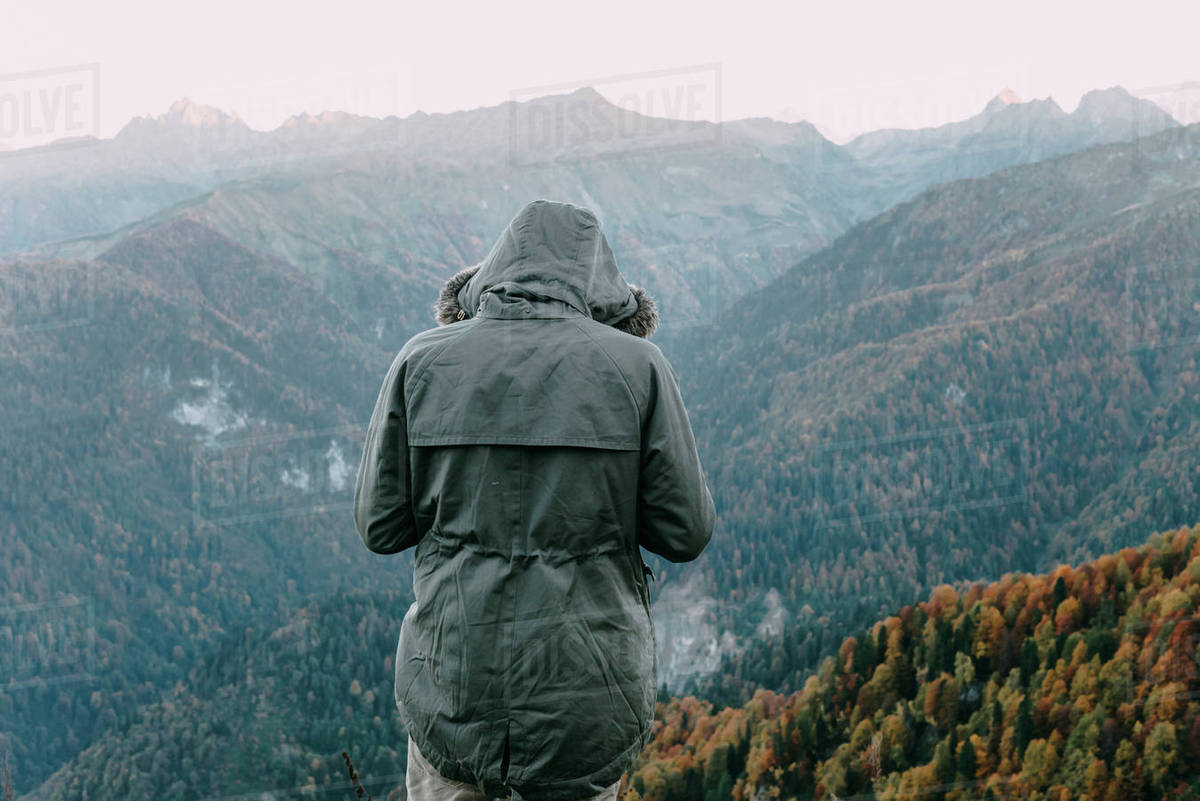 Man wearing coat looking at valley - Stock Photo - Dissolve