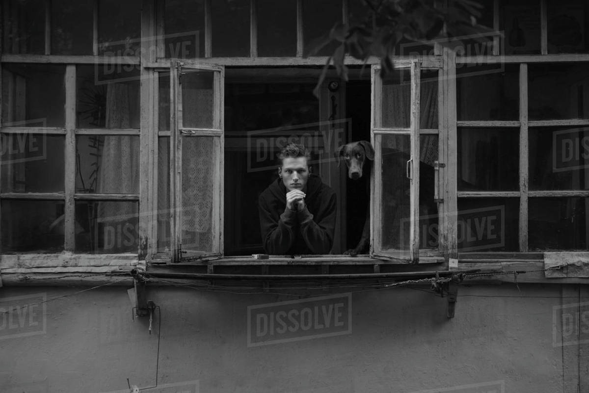 Man leaning in window with dog - Royalty-free Stock Photo | Dissolve