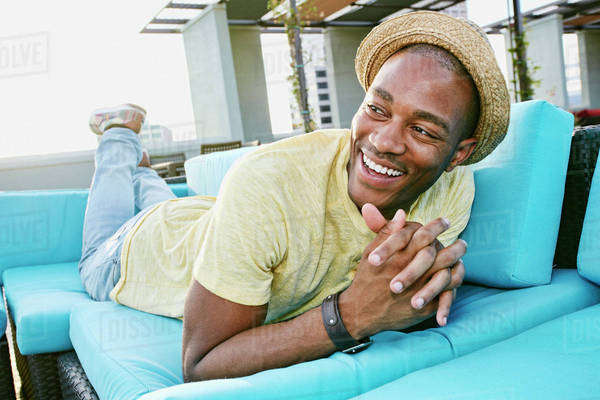 Black man relaxing on sofa on urban rooftop - Royalty-free Stock Photo ...