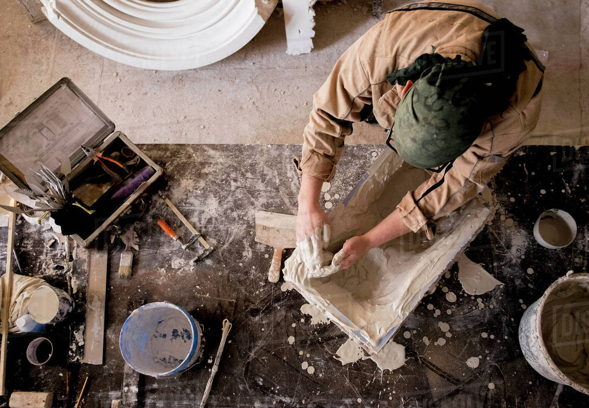 Caucasian artist spreading plaster into mold with hands - Royalty-free ...