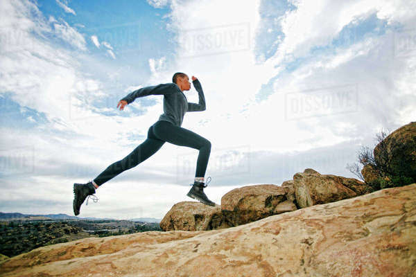 Black woman running on rock formation - Royalty-free Stock Photo | Dissolve