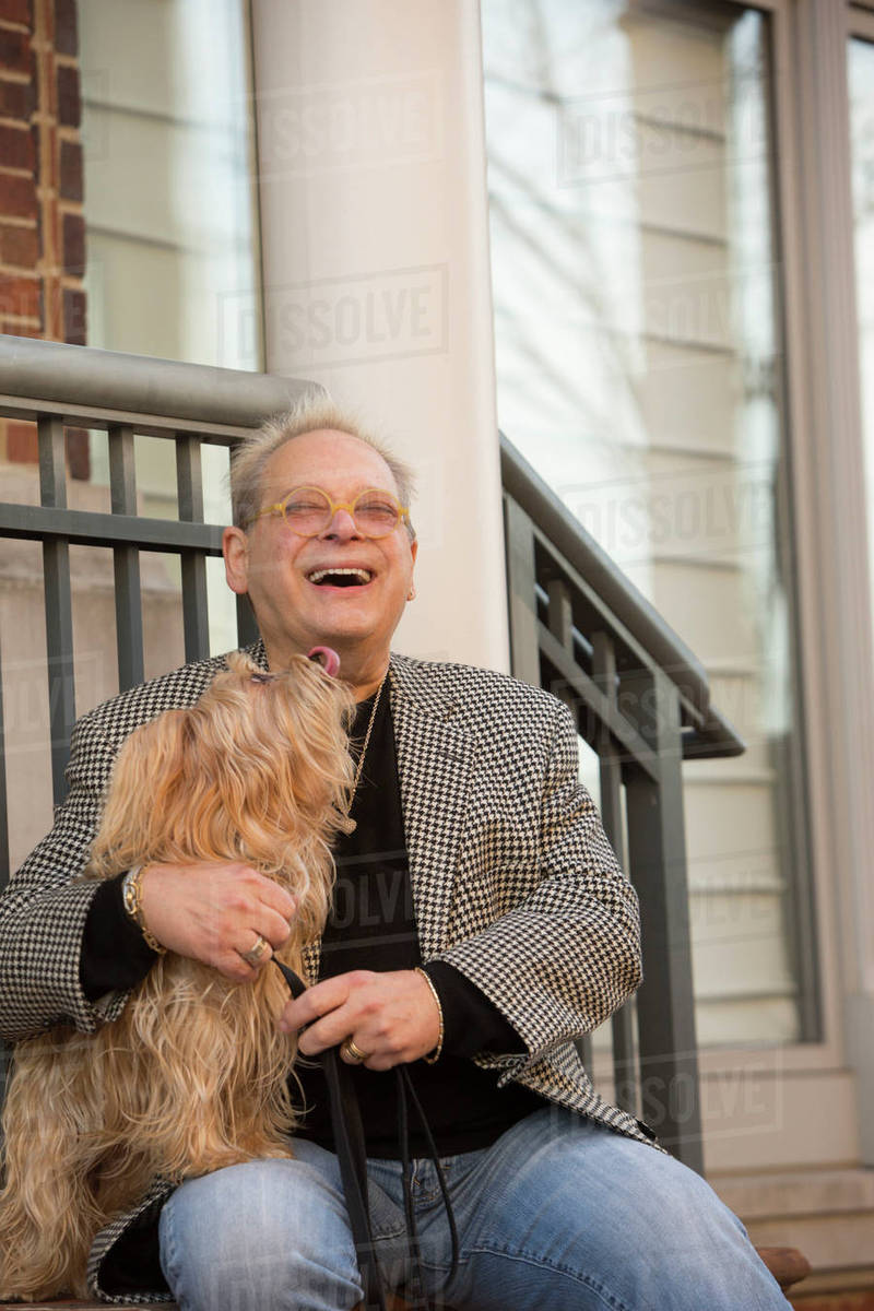 Portrait of Caucasian man sitting on stoop holding dog - Royalty-free ...