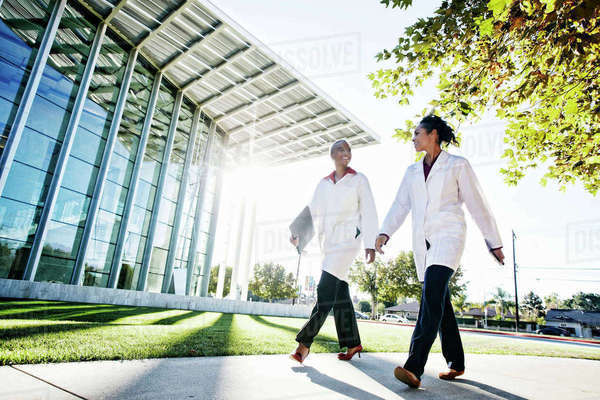 Doctors walking and talking outdoors at hospital - Stock Photo - Dissolve