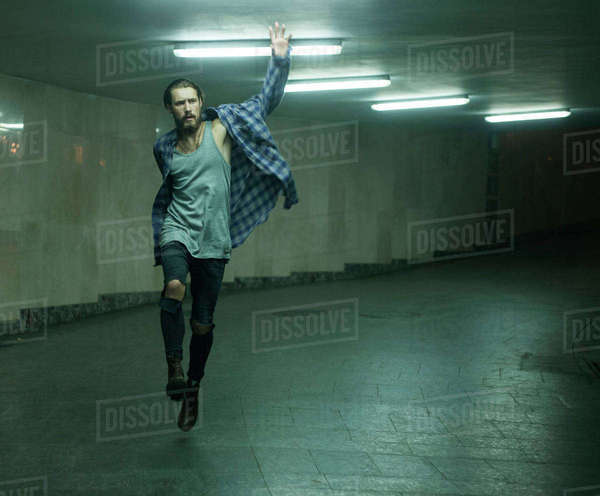 Carefree Caucasian man skipping in tunnel - Stock Photo - Dissolve