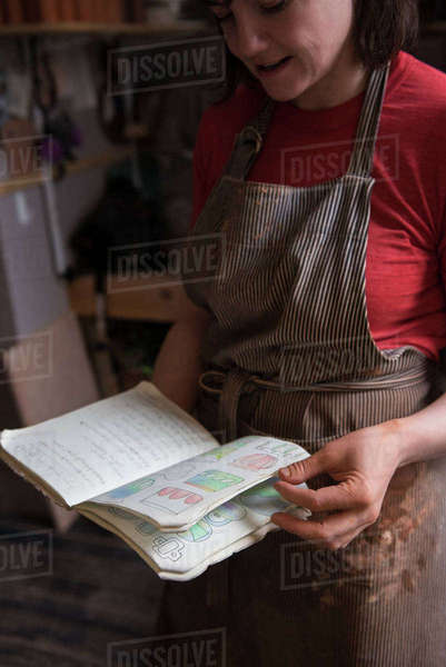 Caucasian woman examining drawings in book - Royalty-free Stock Photo ...