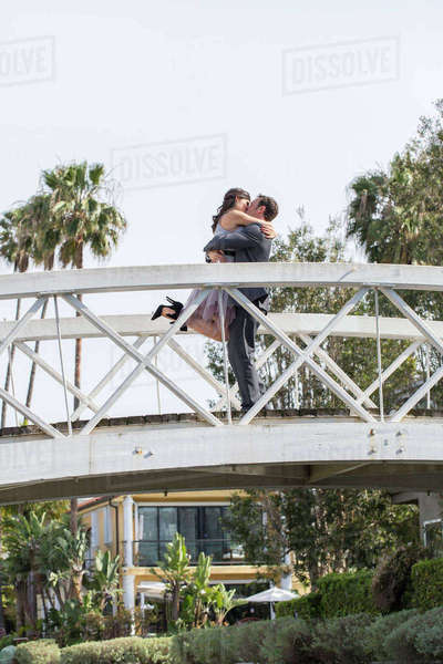 Kissing couple celebrating on bridge - Stock Photo - Dissolve