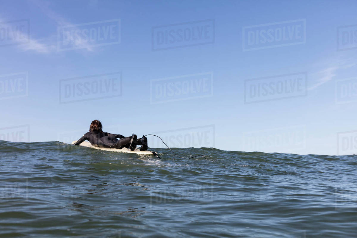 Caucasian man paddling on surfboard - Royalty-free Stock Photo | Dissolve