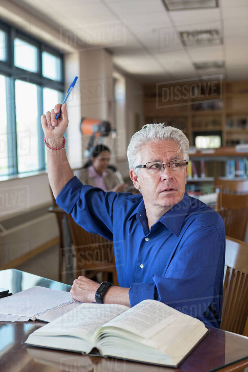 Older man in library raising hand and asking question - Stock Photo ...