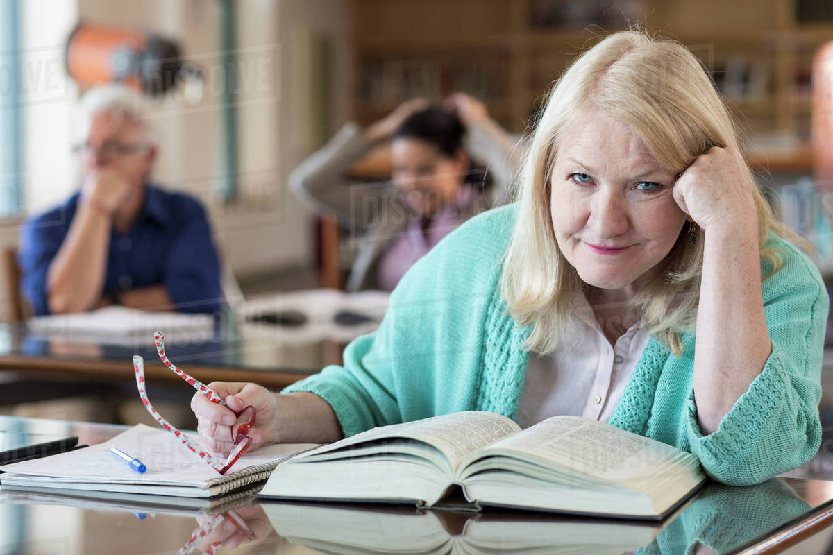 Confused older woman reading book in library - Royalty-free Stock Photo ...