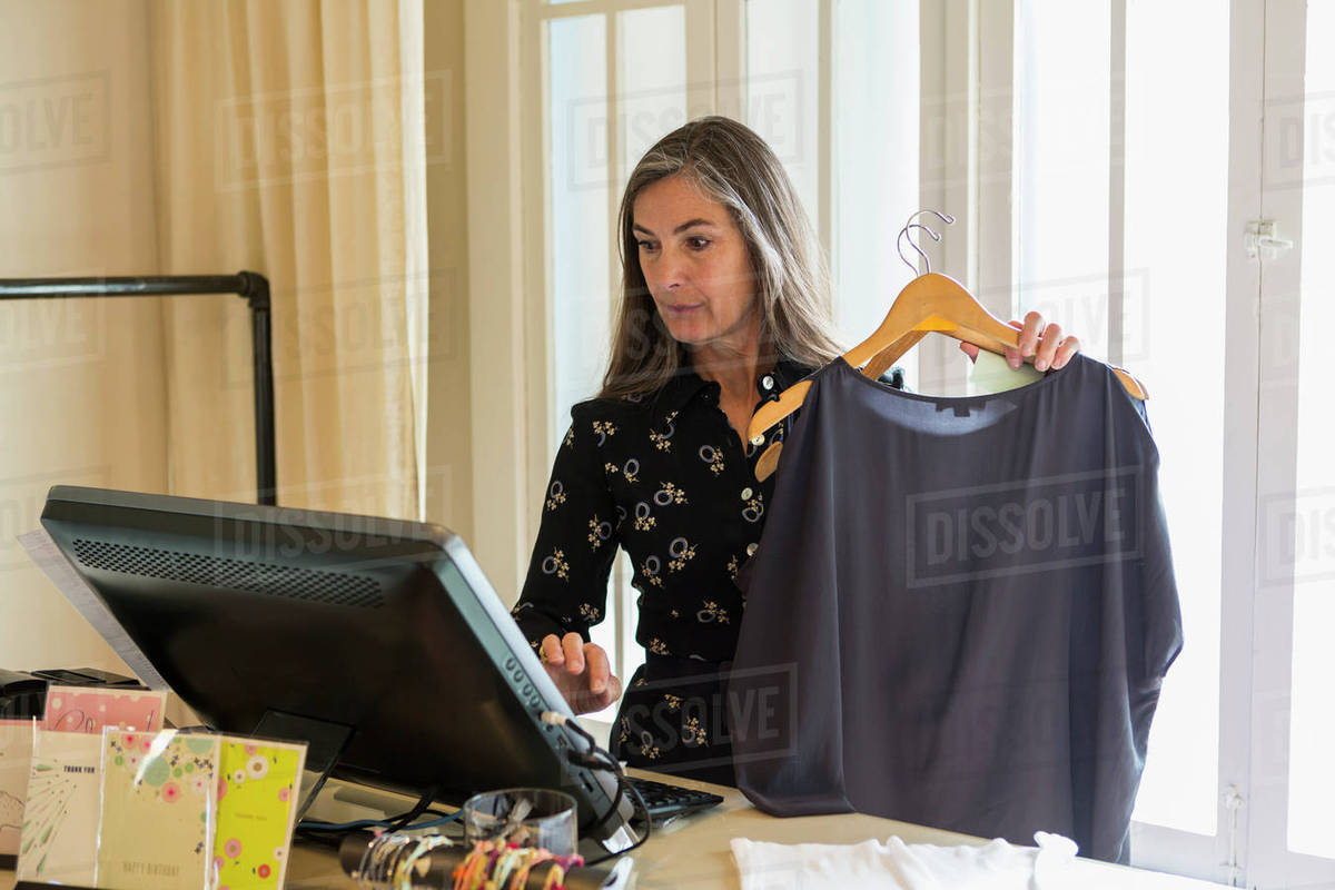 Caucasian woman holding clothing using computer - Royalty-free Stock ...