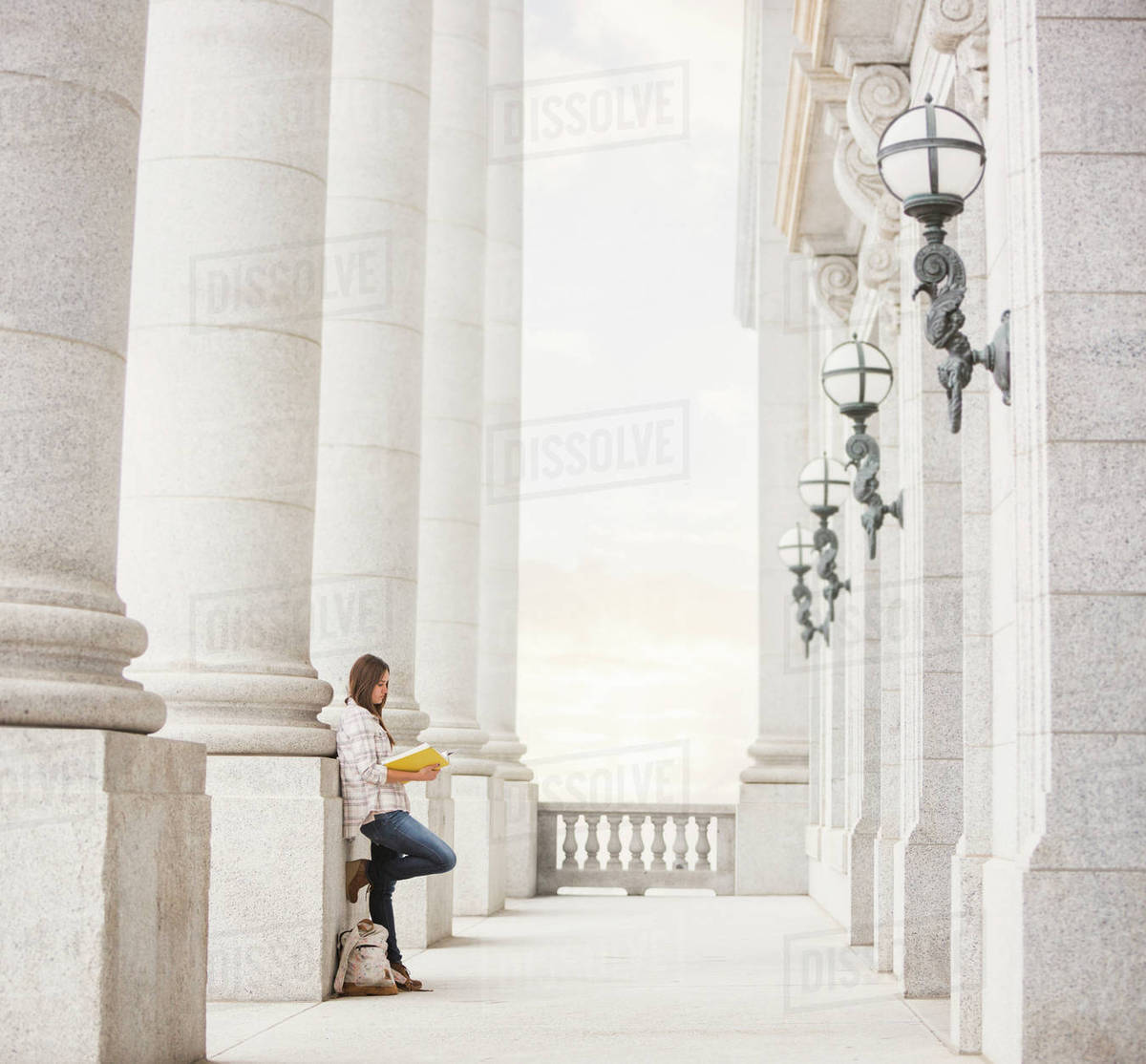 Caucasian woman leaning on pillar reading notebook - Royalty-free Stock ...