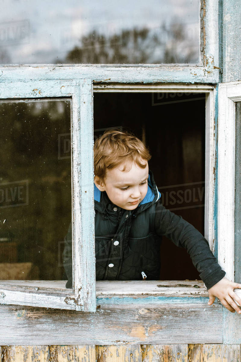 Caucasian boy opening window - Stock Photo - Dissolve