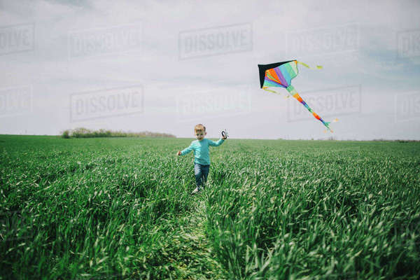 Caucasian boy flying kite in field - Royalty-free Stock Photo | Dissolve