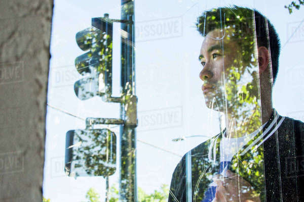 Portrait of serious Chinese man behind window - Stock Photo - Dissolve